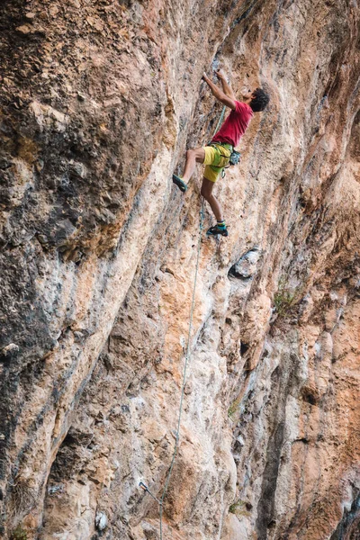 A strong man climbs a cliff. Climber overcomes a difficult climbing ...