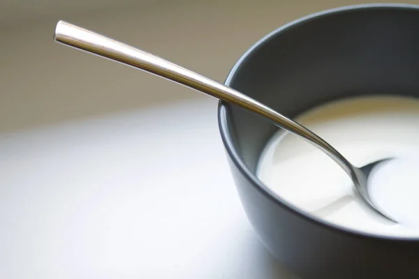 A plate of milk and a spoon close up on white table. Stock Photo by ...
