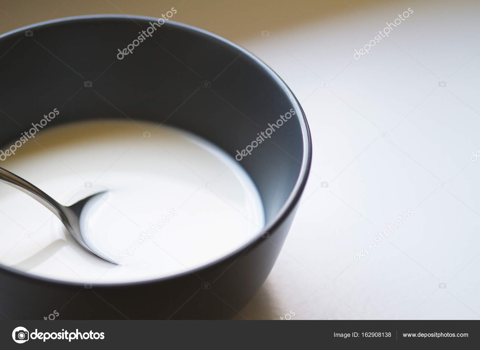 A plate of milk and a spoon close up on white table. Stock Photo by ...
