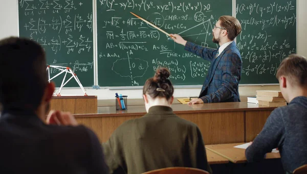 Math teacher pointing at chalkboard - Stock Image - Everypixel