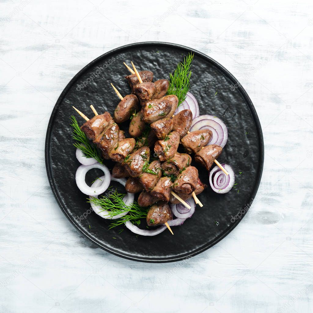 Corazón de pollo al horno en pinchos en un plato negro. Carne de pollo ...