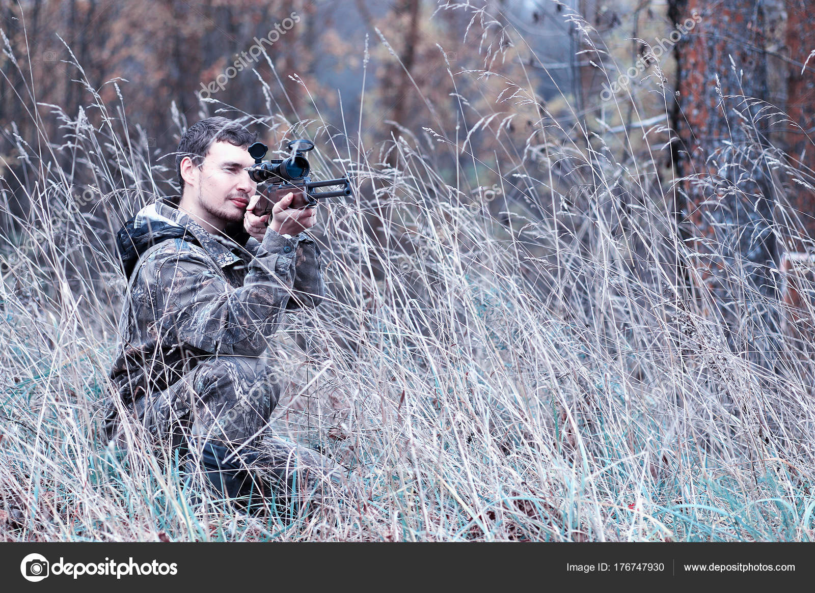 A man in camouflage and with a hunting rifle in a forest on a sp ...