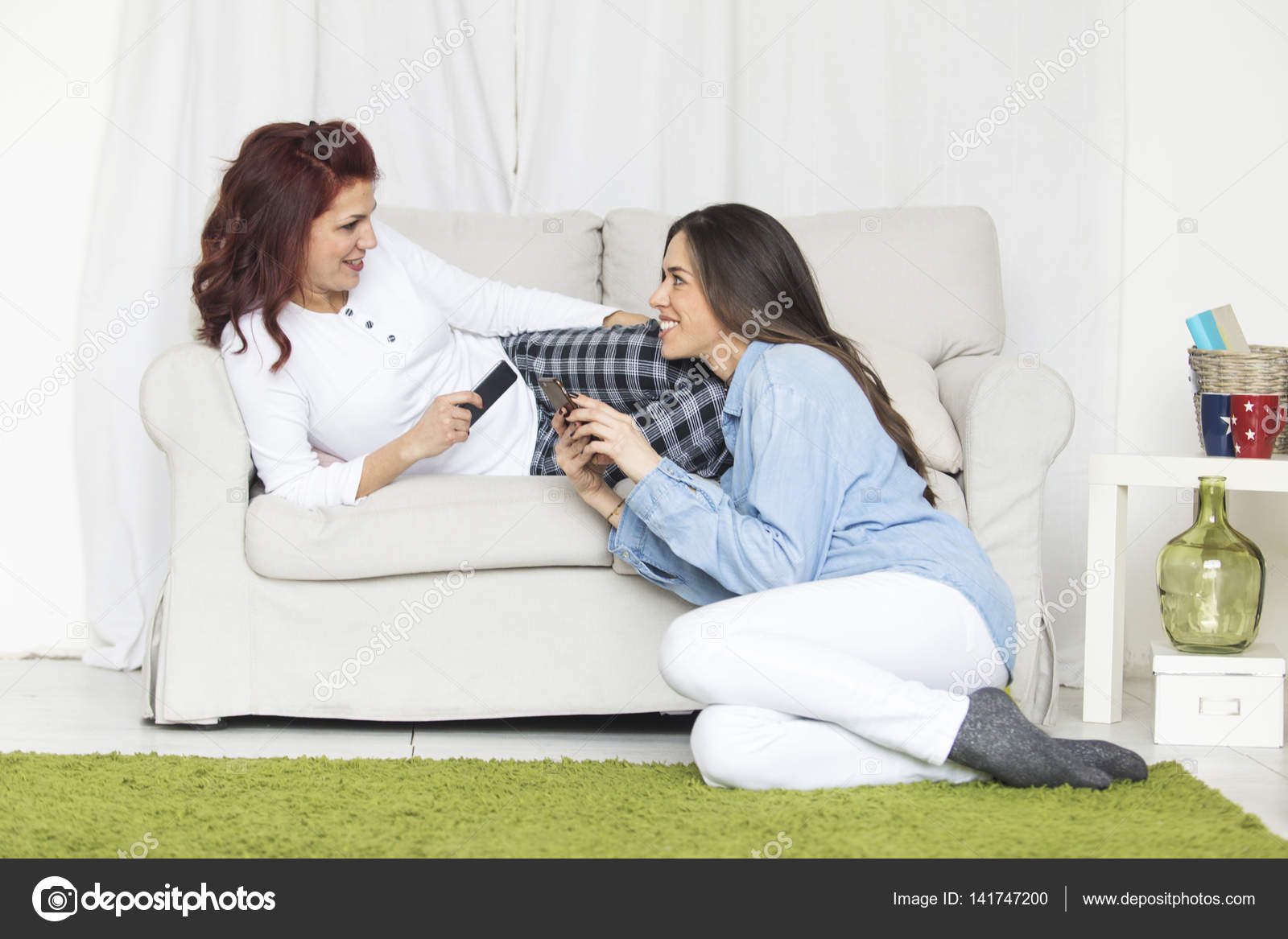Female friends having fun together using smartphones — Stock Photo © Nikodash #141747200