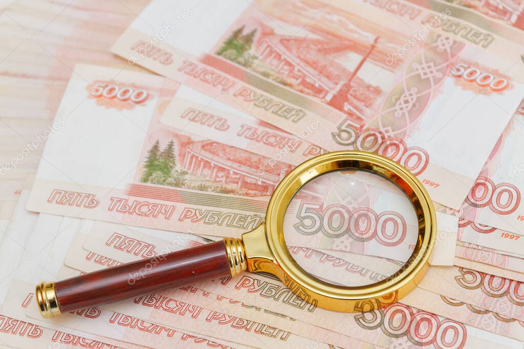Una lupa con asa de oro se coloca encima de los billetes rusos de cinco ...