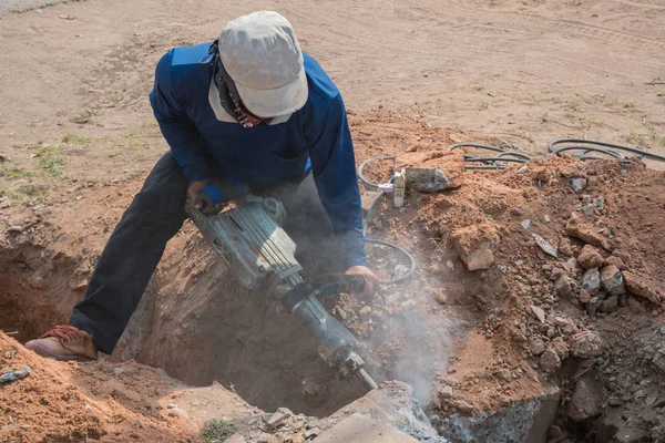 Worker drilling cement concrete floor with machine at constructi ...