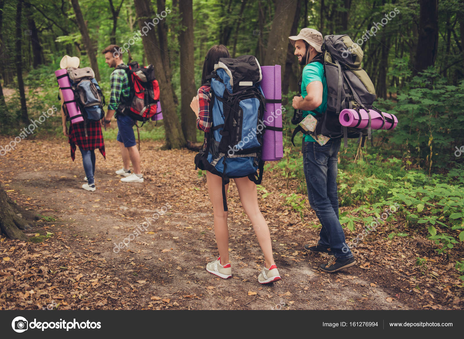 Rear view of two cheerful couples hiking, talking, having fun to ...