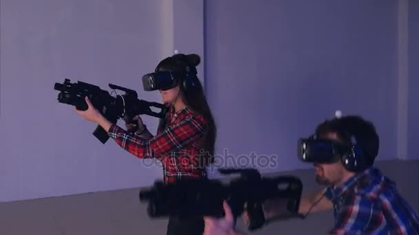Young couple playing VR shooter game with virtual reality guns and ...