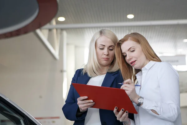 Woman signing a car insurance policy, the agent is pointing at the ...