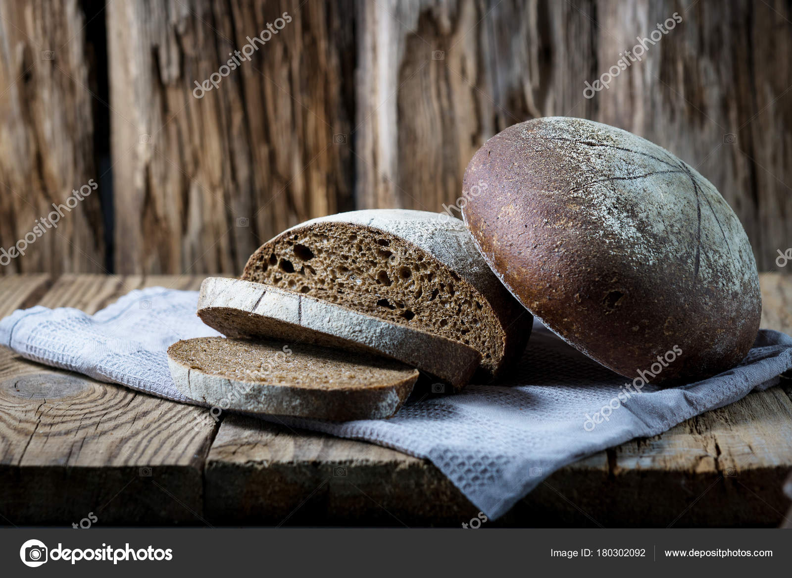 Round rye bread and whole pieces on a fabric napkin on wooden ...