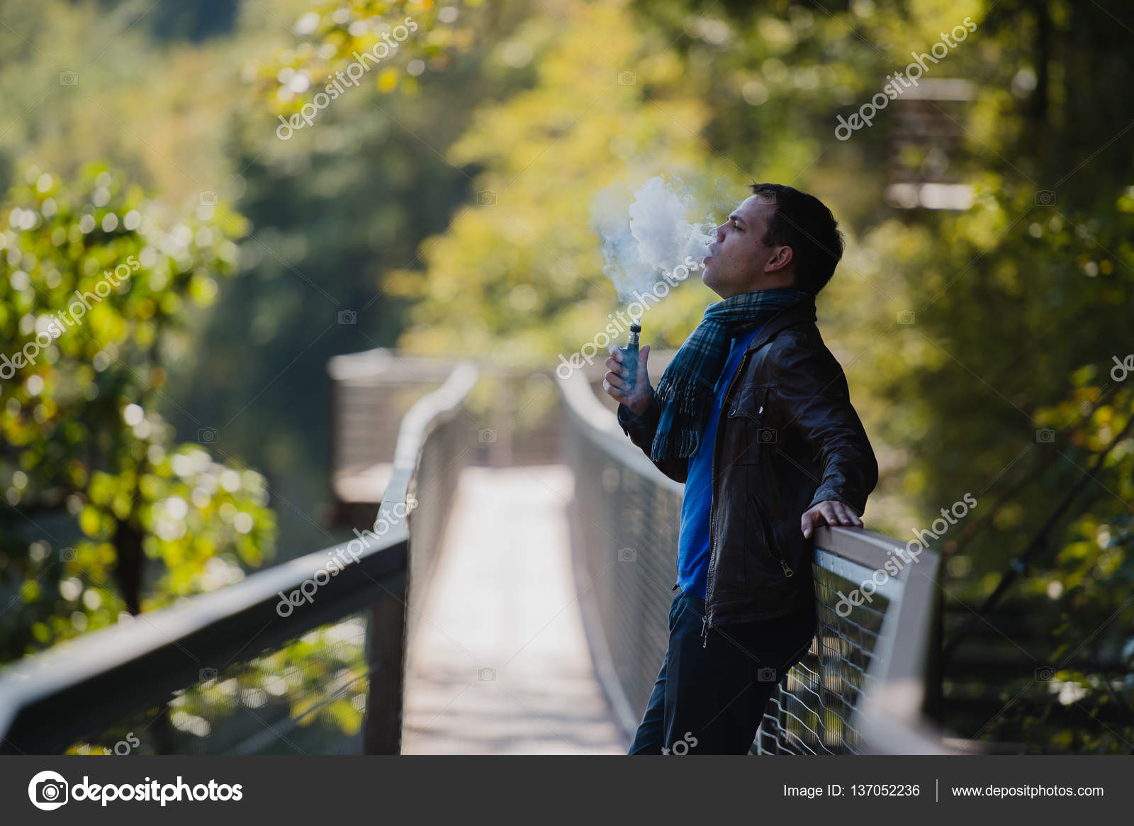 Young man with custom box mode vape device vaping an electronic ...