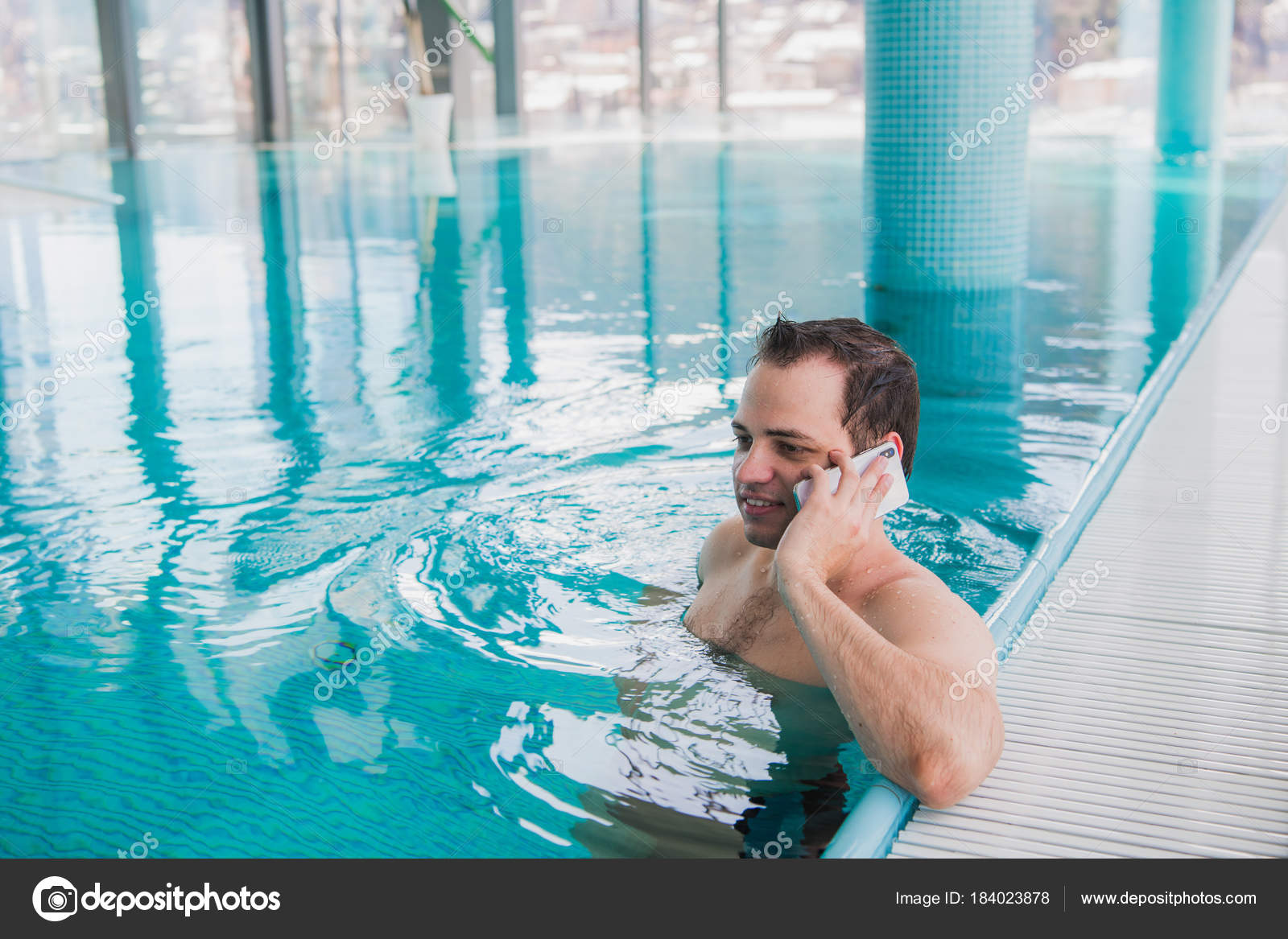 Man talking on cell phone inside the swimming pool at luxury hotel ...