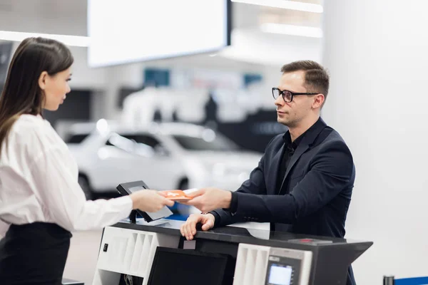 Side view of handsome man wearing glasses giving passport to staff at ...
