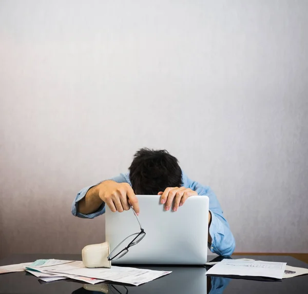 Work stress concept of man facing down computer laptop on desk - Stock ...