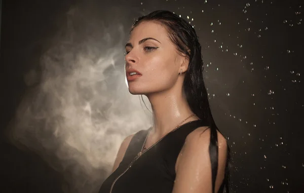 Young beautiful woman vaping e-cigarette. Water flowing on woman face ...