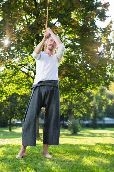 Man practising slack line in park - Stock Image - Everypixel