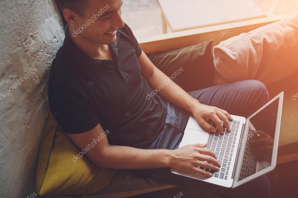 Работаю дома Побочное изображение молодого человека работающего на ноутбуке сидящего на