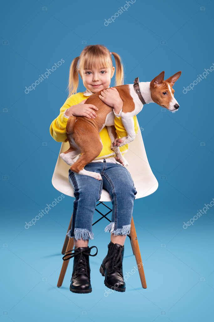 Adorable niño pequeño con coletas sonriendo y abrazando al perro ...