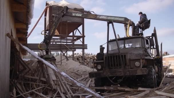 Heavy claw loader unloads timber scraps from heavy truck at sawmill ...