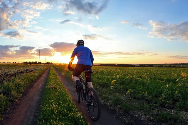 cyclist rides a bicycle on a track at sunset - Stock Image - Everypixel