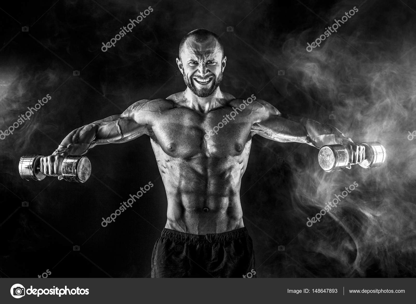Strong sportsman lifting heavy dumbbell in smoke Stock Photo by ©zamuruev 148647893