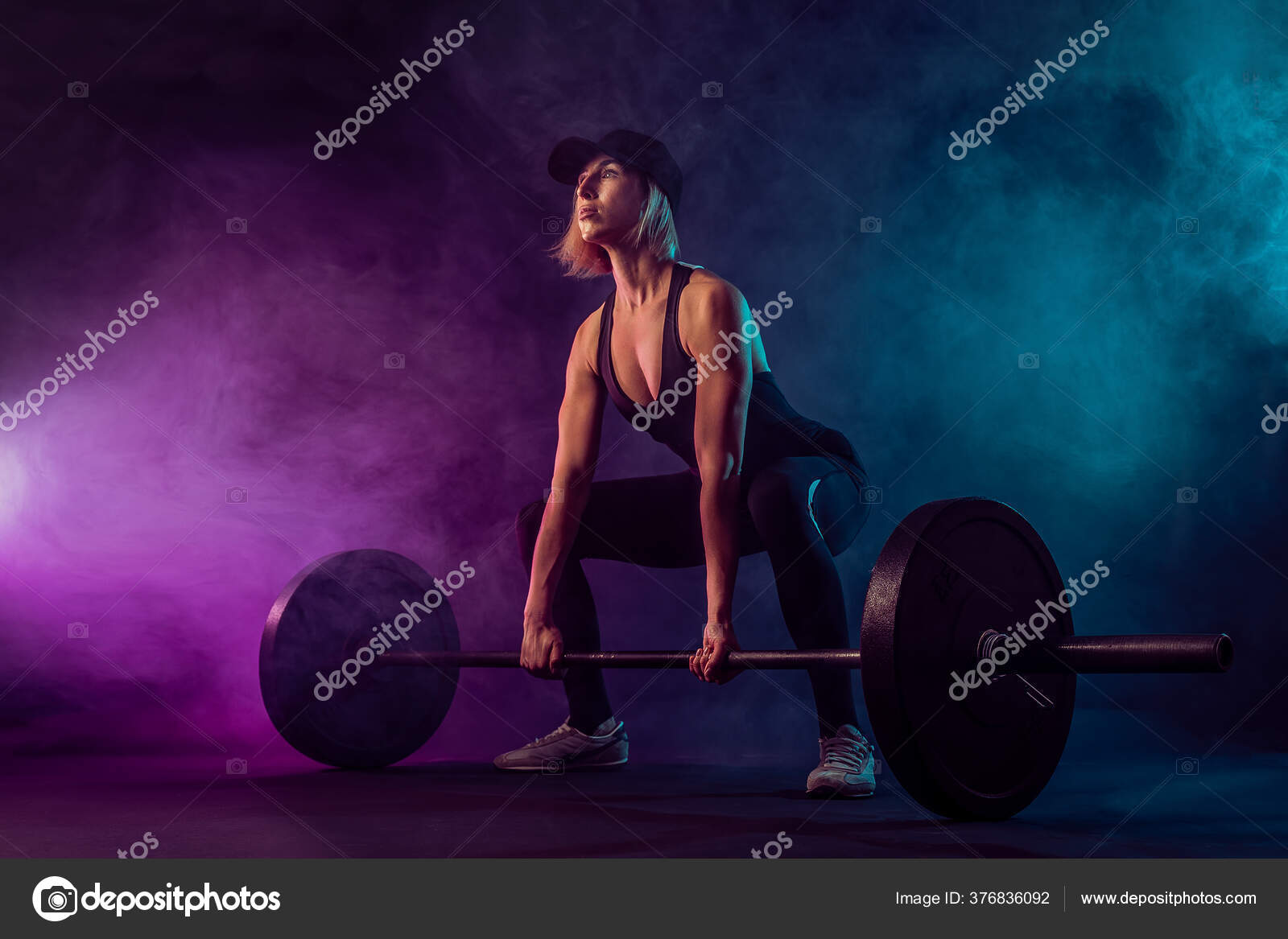 Side view of female bodybuilder doing deadlift using barbell. Srtong ...