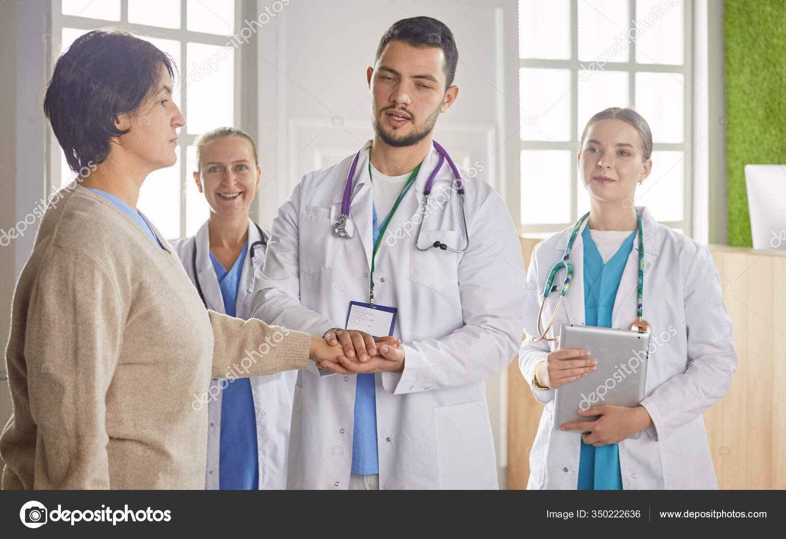 Patient with a group of doctors at the background Stock Photo by ...