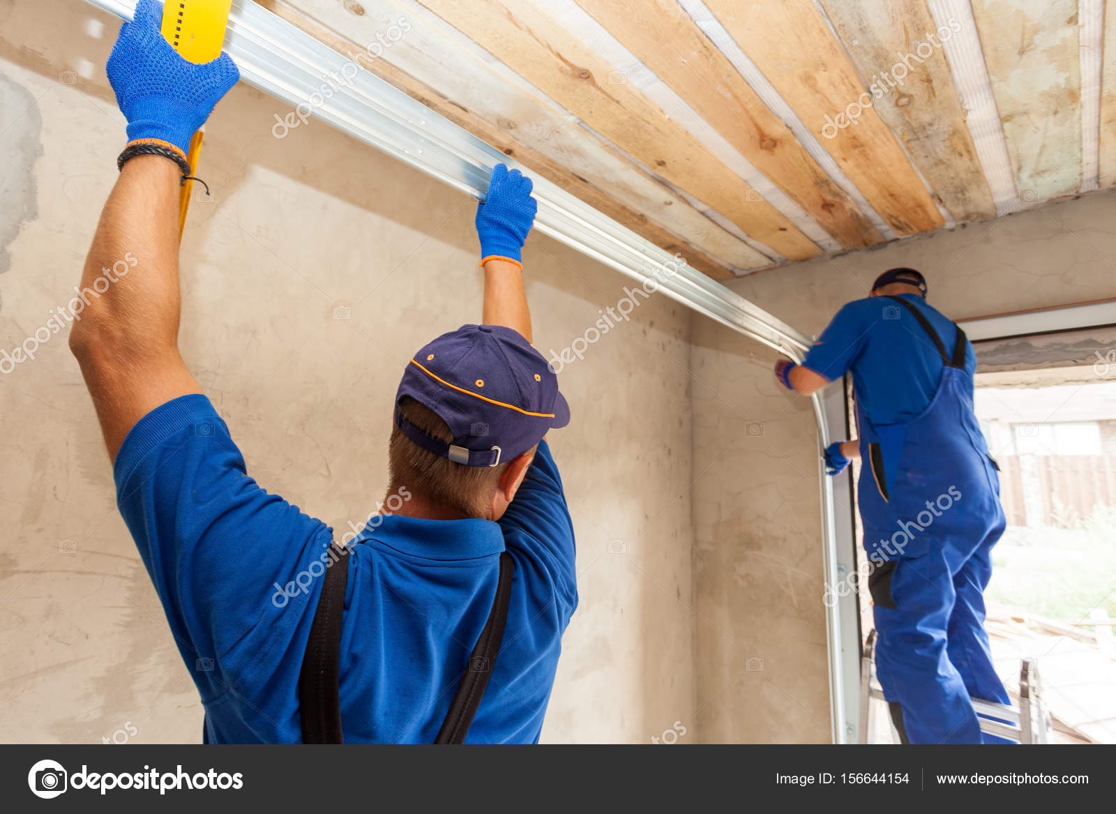Garage doors installation. Workers installing Post Rail and Spring ...