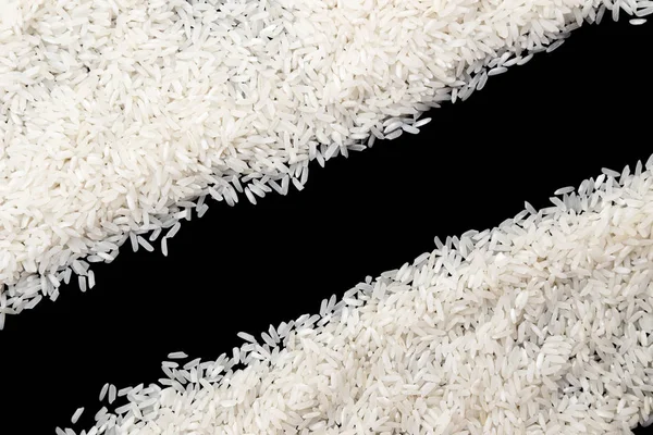 White uncocked rice scattered on black background. Copy space fo ...