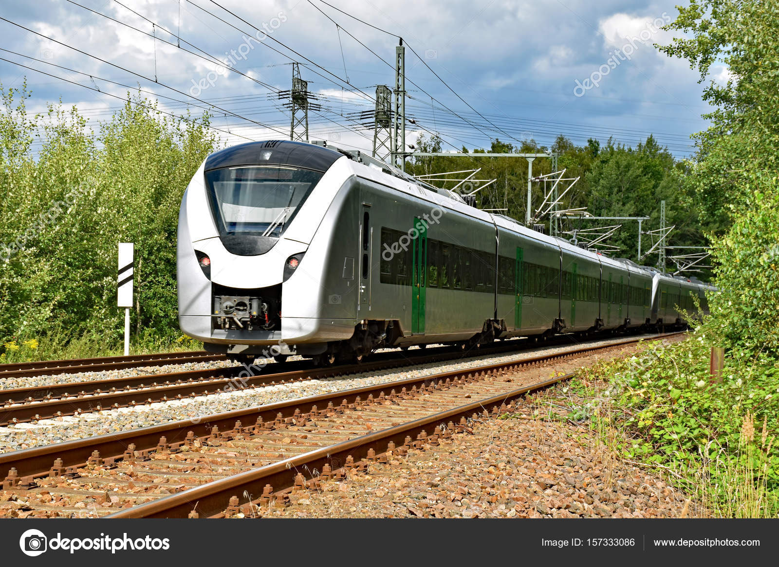 A modern electric regional train runs on a multi-lane track through ...