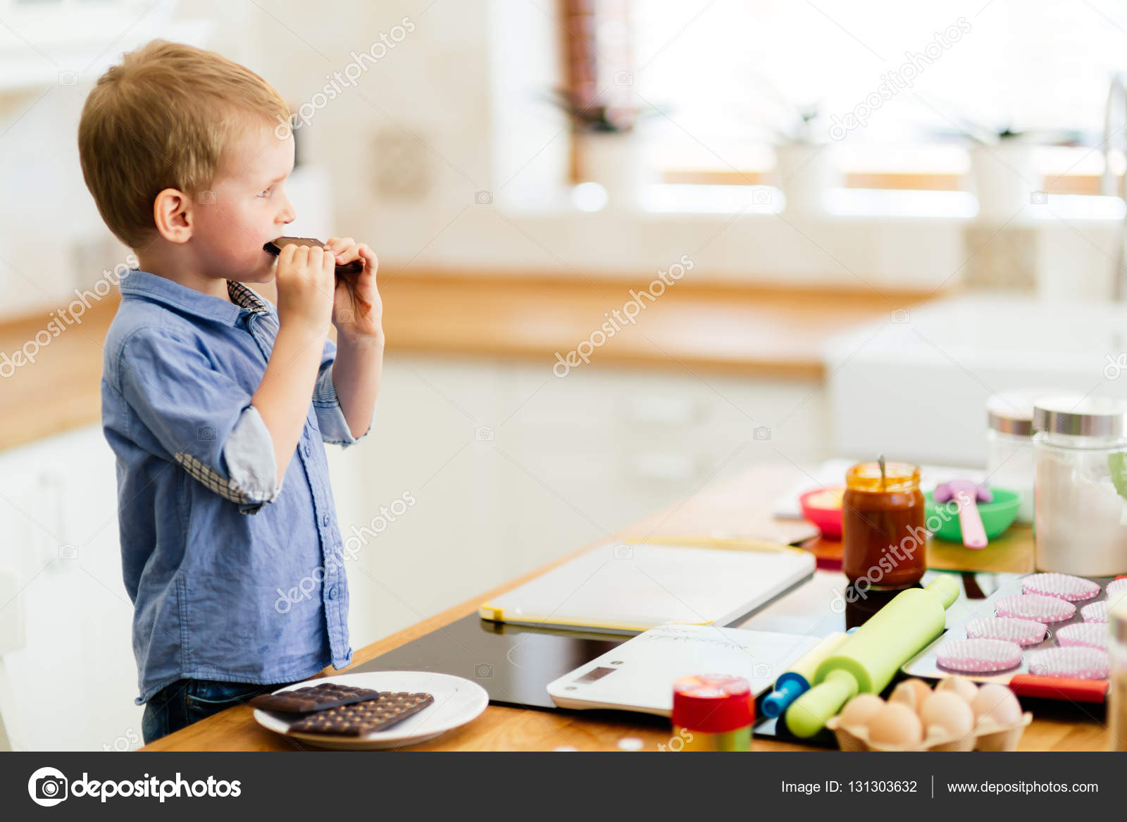 Child tasting chocolate bar in kitchen Stock Photo by ©nd3000 131303632