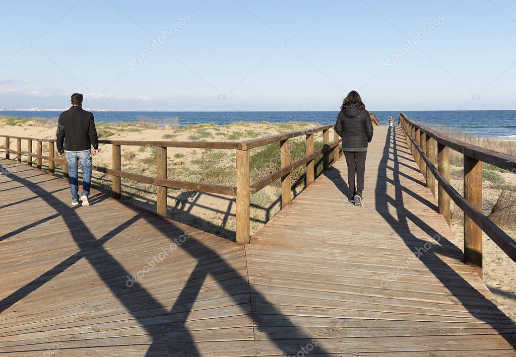 Couple going by different path on a wooden walkway in Arenales d ...