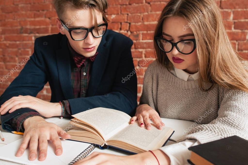 Joven hombre y mujer leyendo libro de texto de cerca 2023