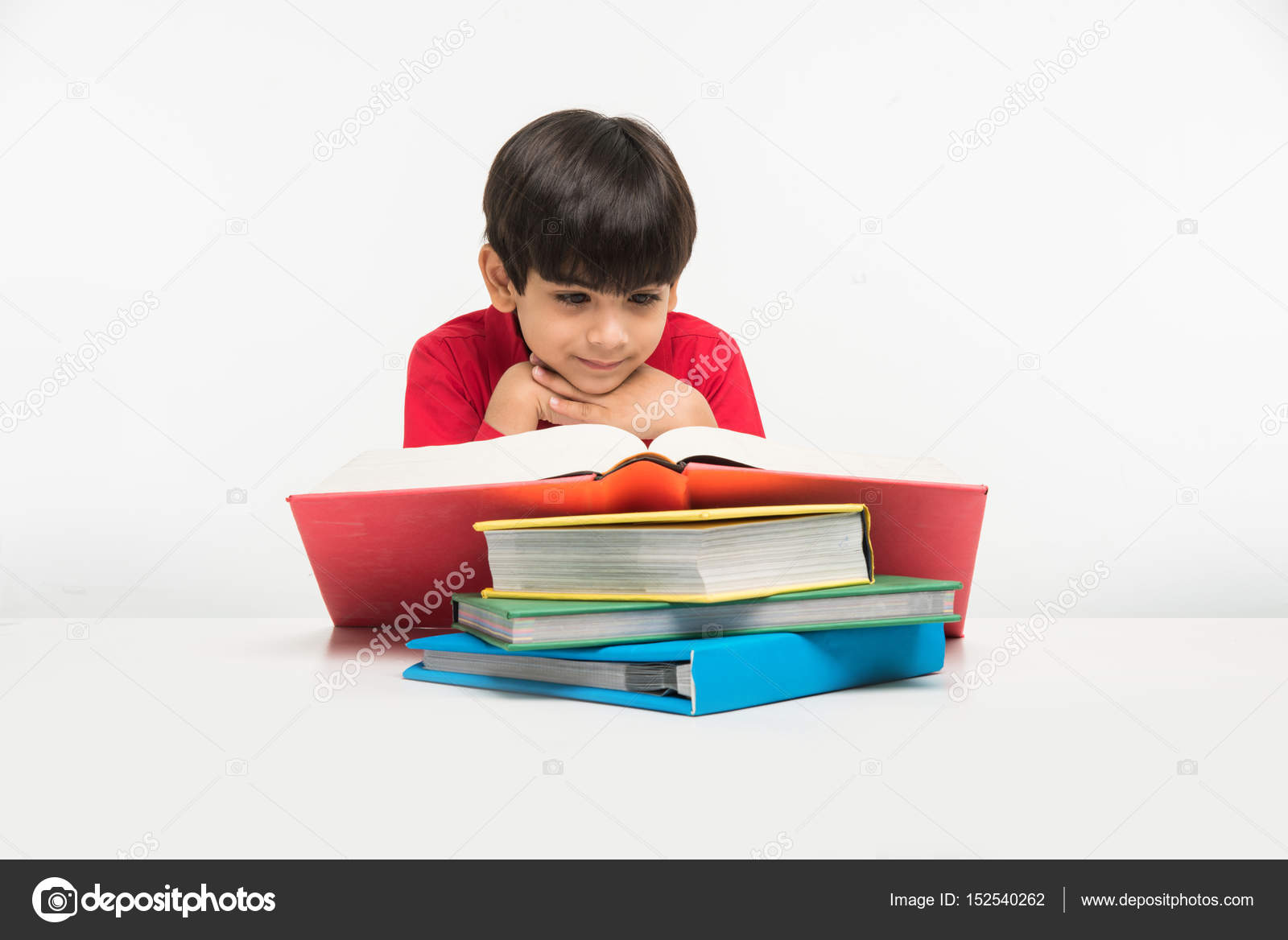 Indian cute little boy or kid reading book over study table, isolated ...