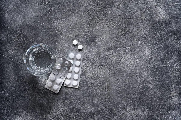 Tablets and glass of water on a concrete background. - Stock Image ...