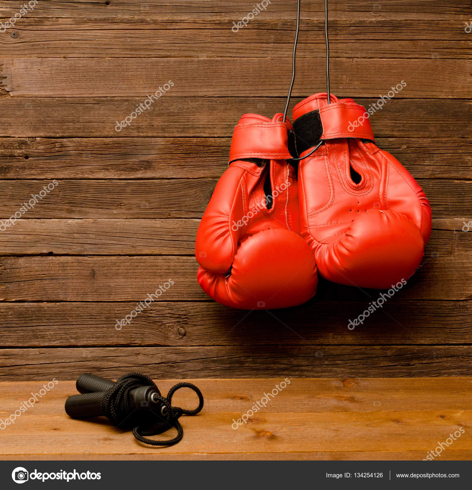 Two red boxing gloves hung on a wooden brown background, skipping rope ...