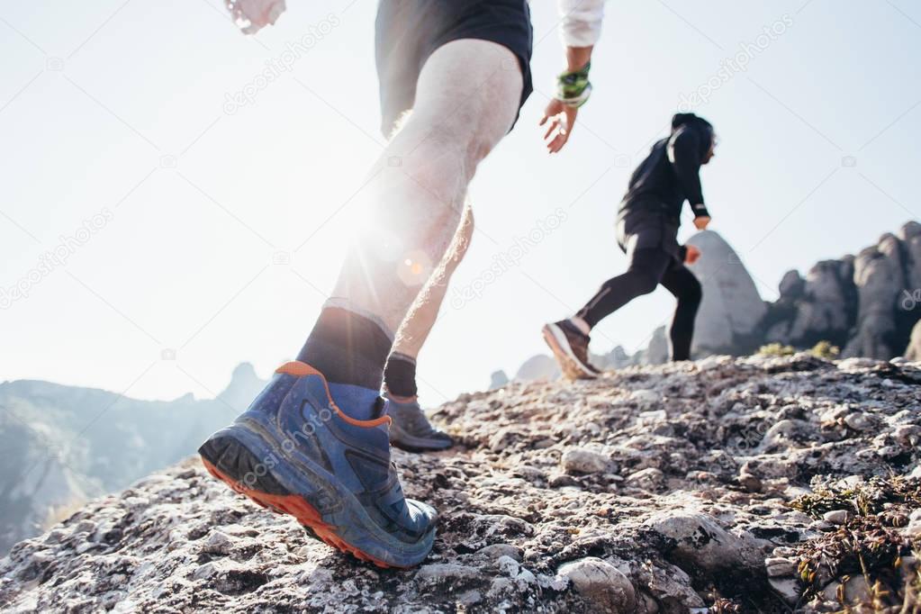 Dos amigos o atletas corren en terreno rocoso de montaña en el camino o ...