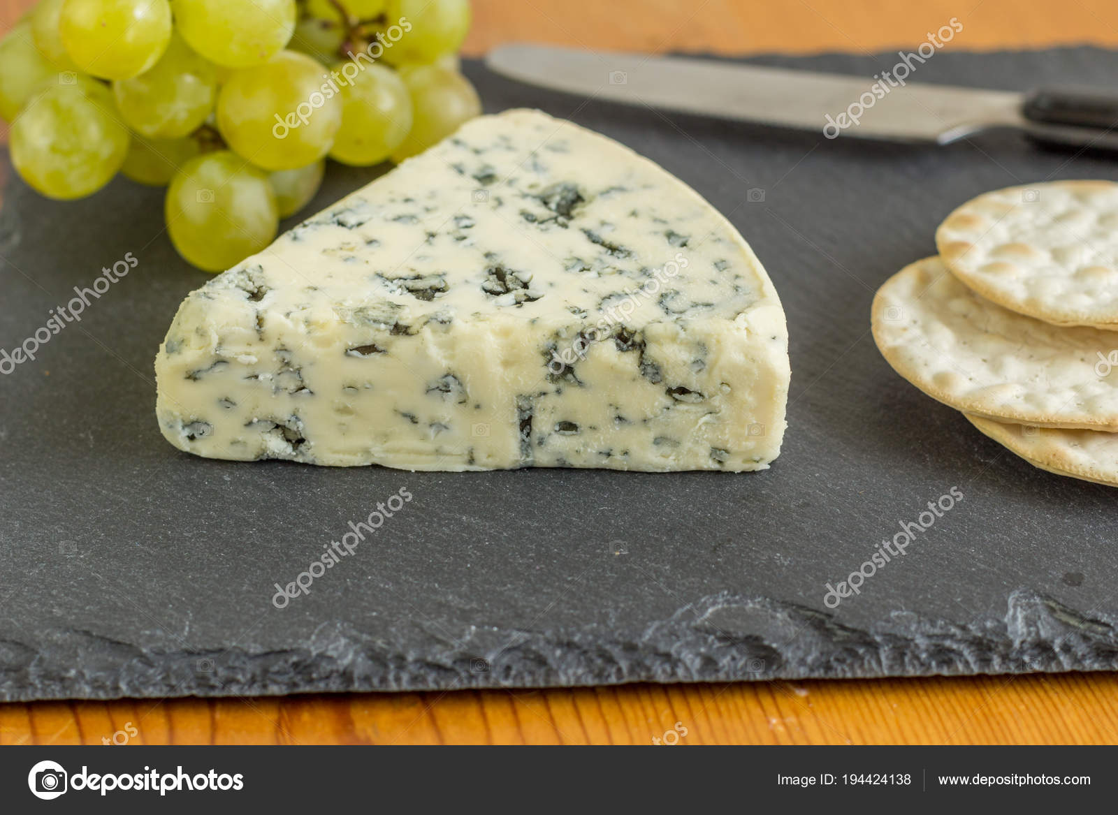 Stilton blue mold cheese wedge close up on black slate cheese board ...