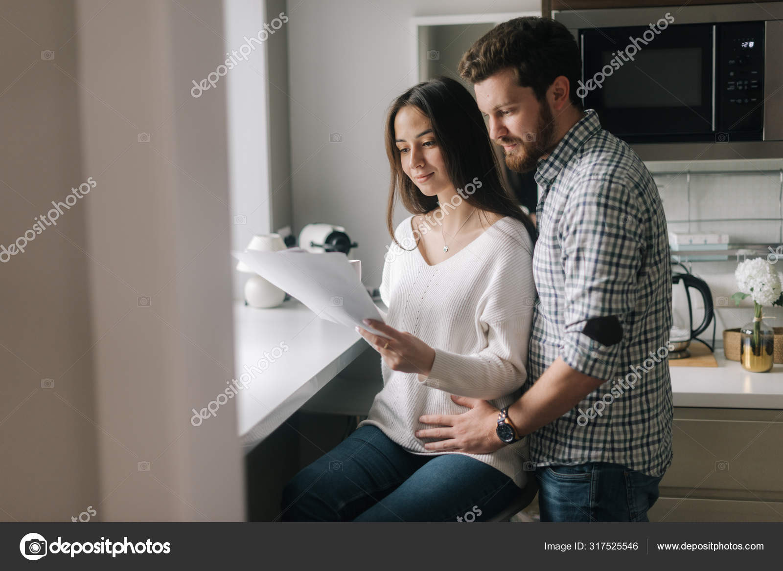 Smiling young couple reading documents at home in the kitchen near the ...