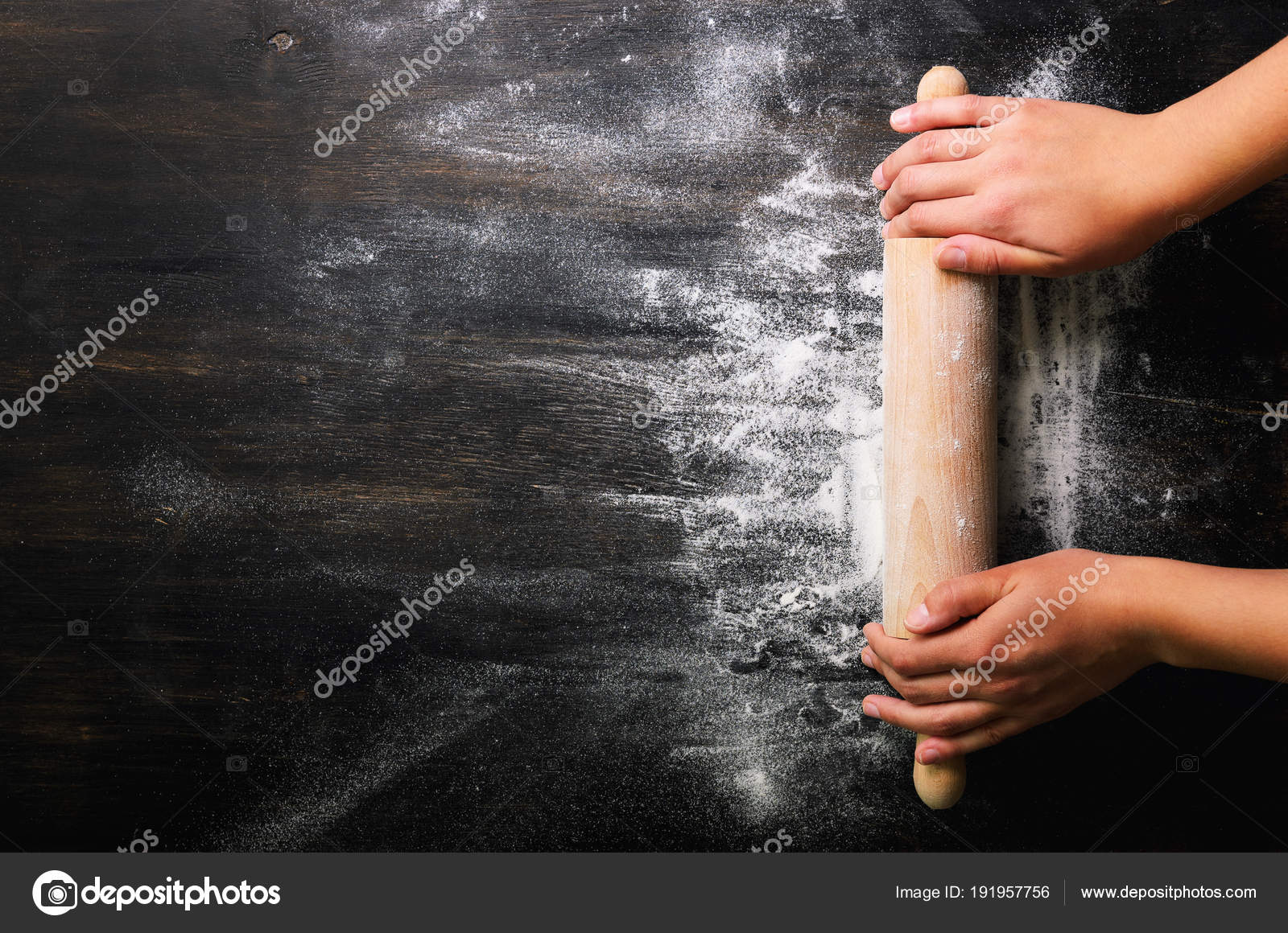 Girl hands keep rolling pin with flour on dark black table, baking ...