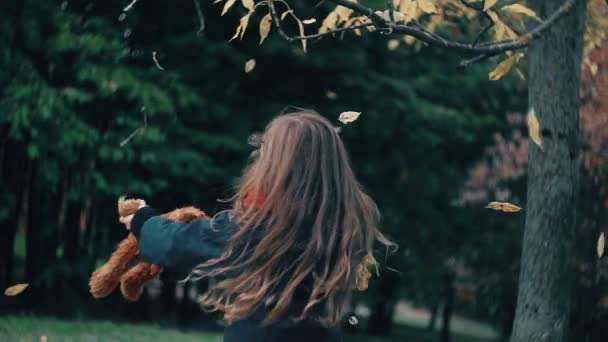 Funny, cheerful cute little girl close-up collects yellow autumn leaves ...
