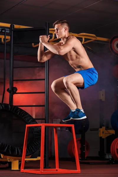 Man box jumping at a crossfit style gym. - Stock Image - Everypixel