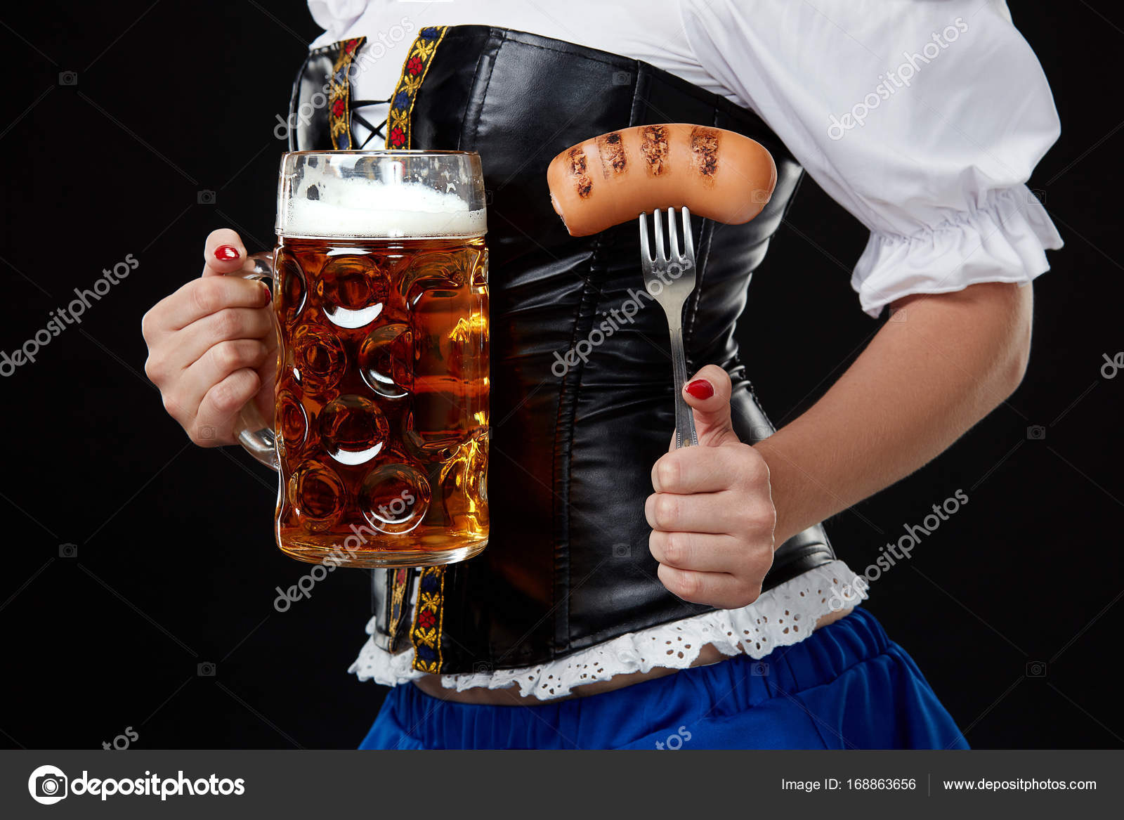 Young woman with dirndl holds Oktoberfest beer stein. On black ...