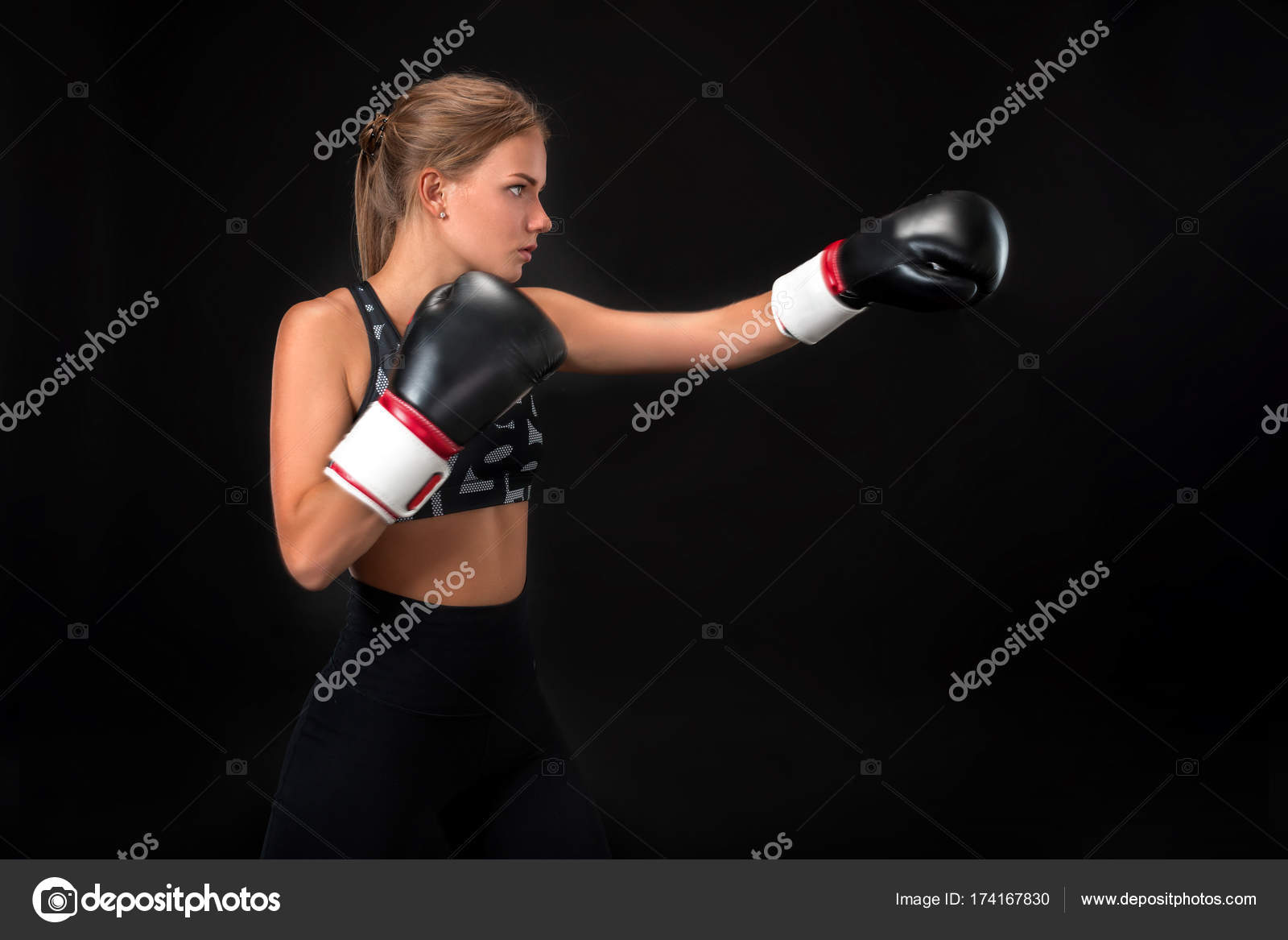 Belle athlète féminine en gants de boxe, en studio sur fond noir ...