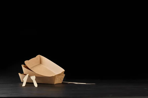 Eco friendly disposable tableware standing on dark surface against ...