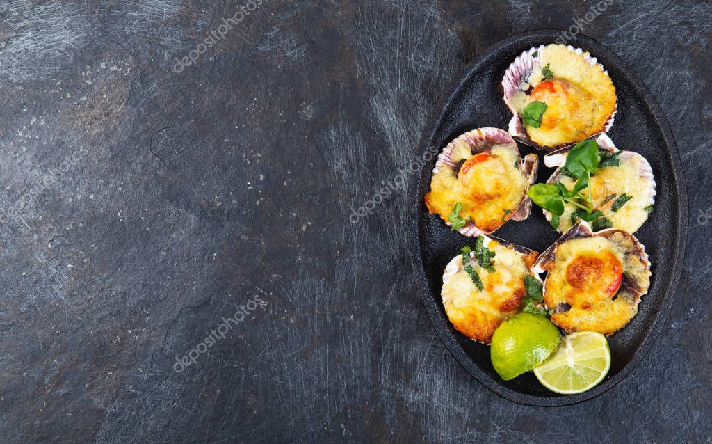 Mariscos al horno vieiras de mariscos con queso y limón. fondo negro. 2023