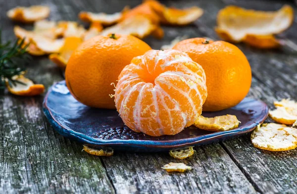 Ripe Mandarin fruit peeled open and place on old rustic look tim ...