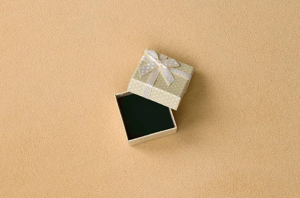 Open small gift box in orange with a small bow lies on a blanket of ...