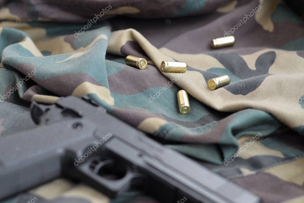 Las balas de 9 mm y la pistola se encuentran en tela verde camuflaje ...