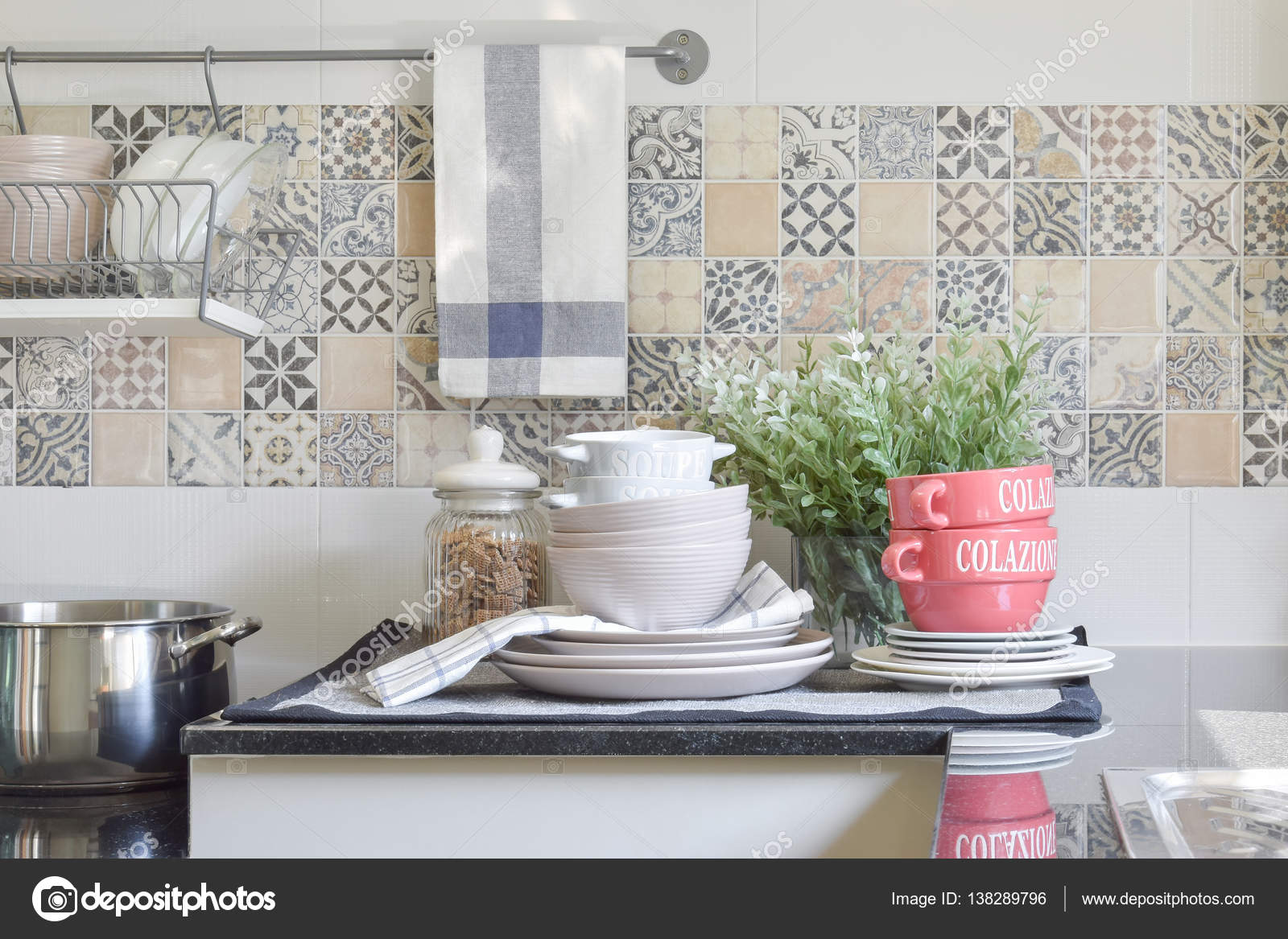 Modern ceramic kitchenware and utensils on the black granite countertop ...