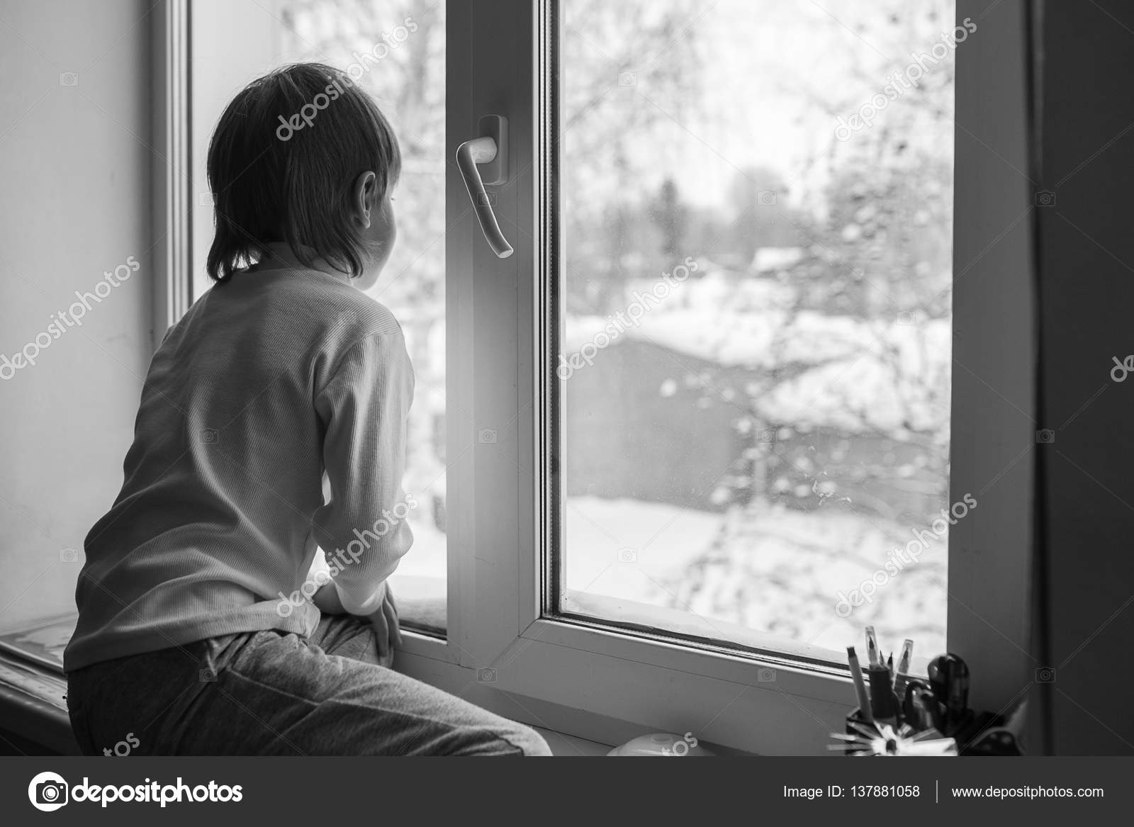 Boy looks out the window on a winter day Stock Photo by ...